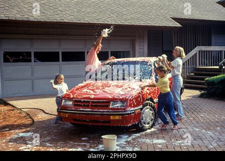 1990 HISTORICAL FAMILY WASHING AUTOMOBILE IN FRONT DRIVEWAY OF SUBURBAN ...