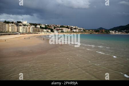 The town's waterfront, sandy beach of La Concha Bay, stormy clouds in ...