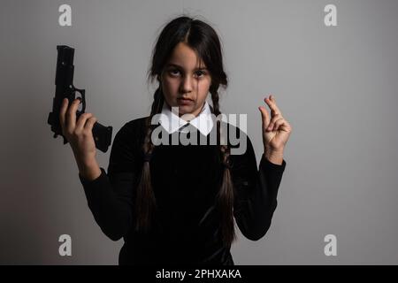 Wednesday Addams. Gothic girl with pistol, weapon Stock Photo - Alamy