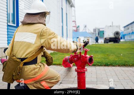 Firefighter sits next to fire hydrant. Back view. Firemen training ...