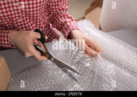 Woman cutting bubble wrap at table in warehouse, closeup Stock Photo ...