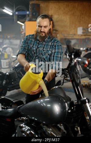 Man biker refueling motorcycle in garage after service repair work ...