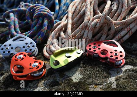 Different belay devices and ropes on rock, closeup. Climbing equipment ...