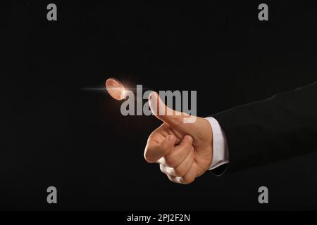 Man throwing coin on black background, closeup. Making decision Stock ...