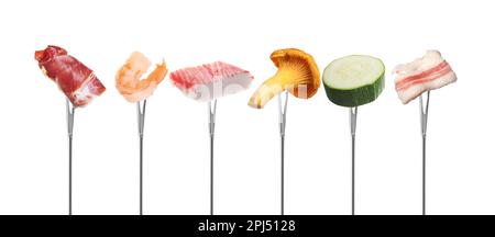 Forks with different tasty ingredients for fondue on white background ...