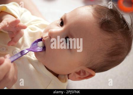 Newborn child drinking water or medicine cough syrup with spoon, close ...