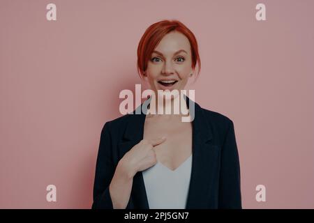 You mean me. Surprised redhead woman pointing herself puzzled raise ...