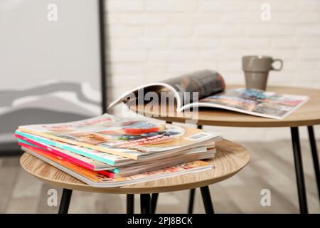 Wooden nesting tables with different magazines and cup of coffee ...