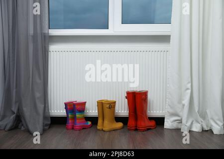 Rubber boots near heating radiator in room Stock Photo - Alamy