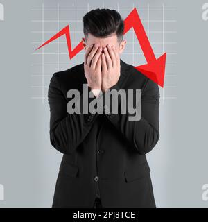 Upset businessman and illustration of falling down chart on light grey ...