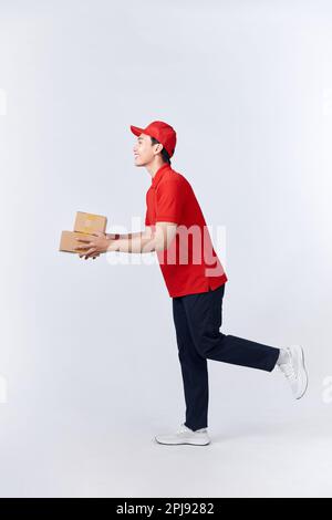 Young delivery man standing with lot of parcel post boxes isolated over ...