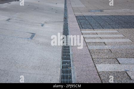 Stainless steel grated flood water storm drain on a Tokyo sidewalk ...