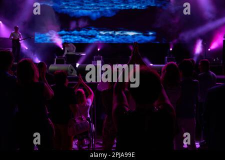 Colourful concert arena with a crowd silhouette against stage lights ...