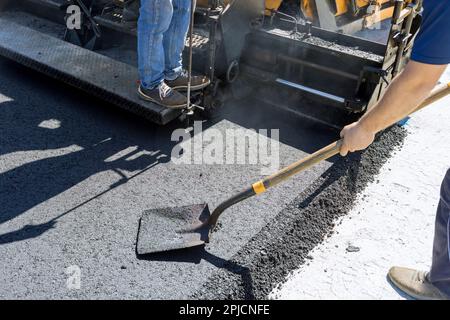 Construction workers placing hot tarmac after installation of new ...