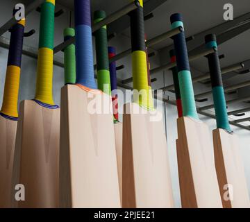 A collection of generic cricket bats with various colorful grips on ...