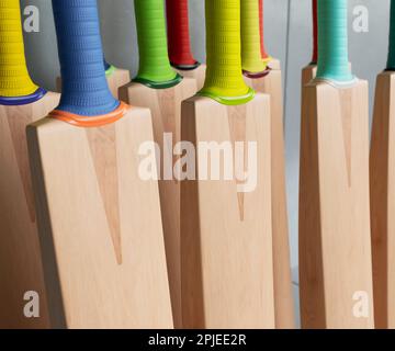 A collection of generic cricket bats with various colorful grips on ...