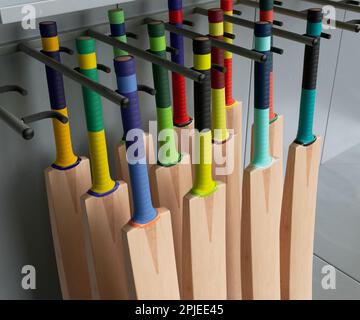 A collection of generic cricket bats with various colorful grips on ...