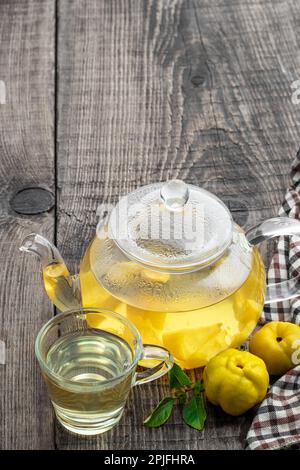 Hot quince tea in transparent teapot with fresh fruits on wooden table ...