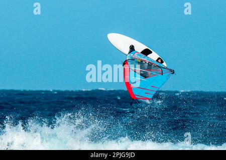 summer sports: windsurfer making an acrobatic jump in the waves and ...