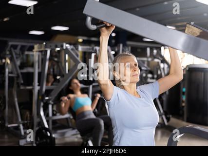 Senior woman doing lat pull-down on lever gym machine Stock Photo - Alamy