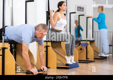 Focused man and women of different ages performing stretching exercises ...