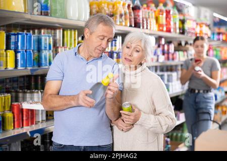 Female customer choosing soft drinks in grocery store, looking at ...