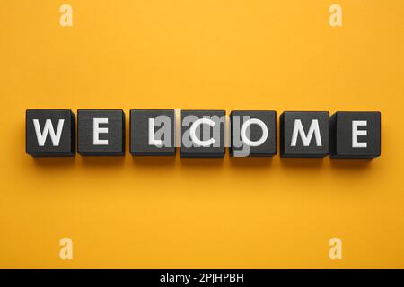 Word Welcome made of black cubes with letters on turquoise background ...