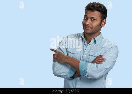 South asian brown guy with folded arms pointing at copy space. Isolated ...