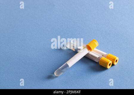 Three sample tubes of clear fluid with yellow lids, on blue background ...