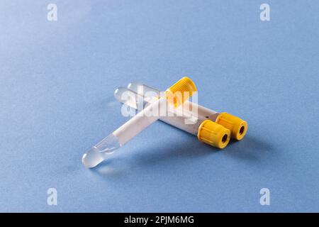Three sample tubes of clear fluid with yellow lids, on blue background ...