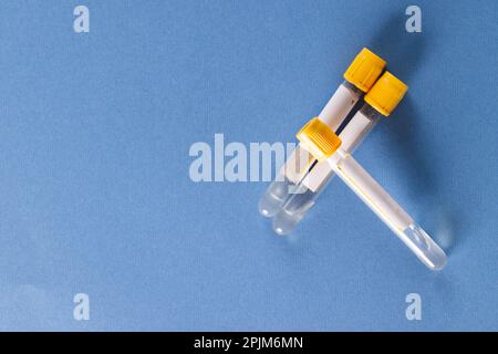 Three sample tubes of clear fluid with yellow lids, on blue background ...