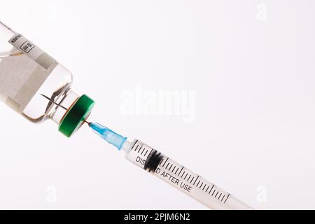 Syringe filling from vial of clear liquid such as insulin, on white ...