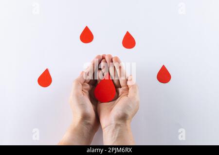 Hands of caucasian woman cupping blood drop, on white background with ...