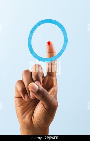 Hand of biracial man with blue ring over bleeding finger, on blue ...