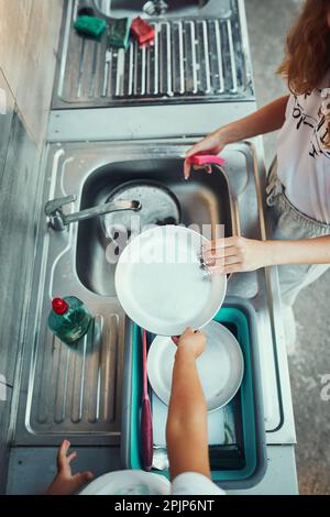 Teenager girl washing up the dishes pots and plates with help her ...