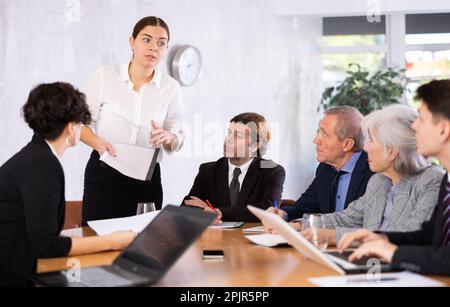 Female director gives instructions to managers in deliberation room ...