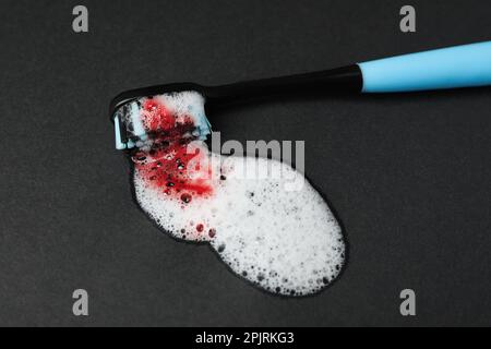 Toothbrush with paste and blood on black background, top view. Gum ...