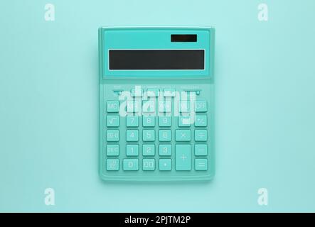 Turquoise calculator on light blue background, top view. Space for text ...