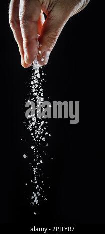 Male hand sprinkling edible salt at black background Stock Photo - Alamy