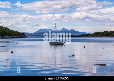 Yacht moored in Glenuig Bay, with Isle of Eigg in distance and ...