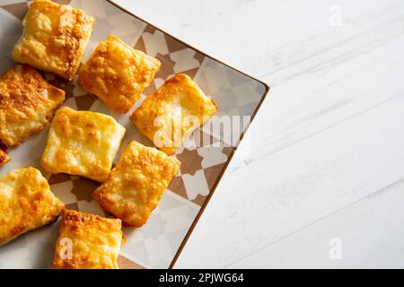 Small, square puff pastries with gratin cheese Stock Photo - Alamy