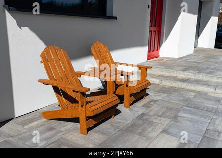 Two wooden chairs connected by a small table standing in front of a ...