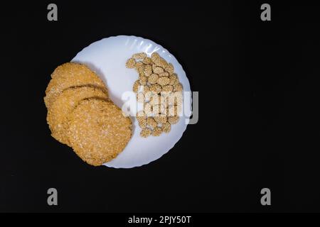 indian traditional sweet tilkut in white plate with black background ...