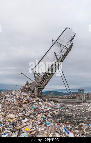 Landfill tipper lifts trailer container to dump all the trash into an ...