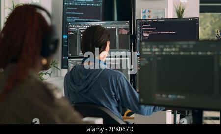 Software programer writing code in front of multiple computer screens ...