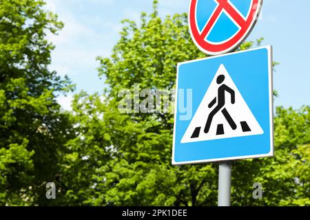 Post with Pedestrian Crossing and No Stopping traffic signs in city on ...