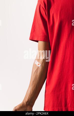 Arm of biracial man with heart sticking plaster and red string with ...