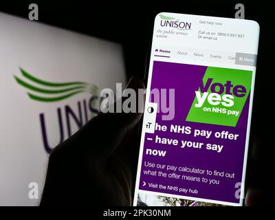 Person holding cellphone with logo of Union of Shop Distributive and ...