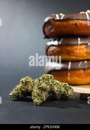 A dry bud of medical marijuana and a donut covered with chocolate icing ...