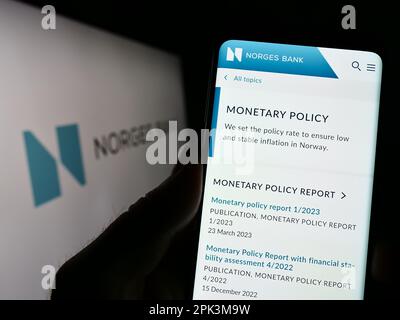 Person holding cellphone with webpage of Norges Bank Investment ...